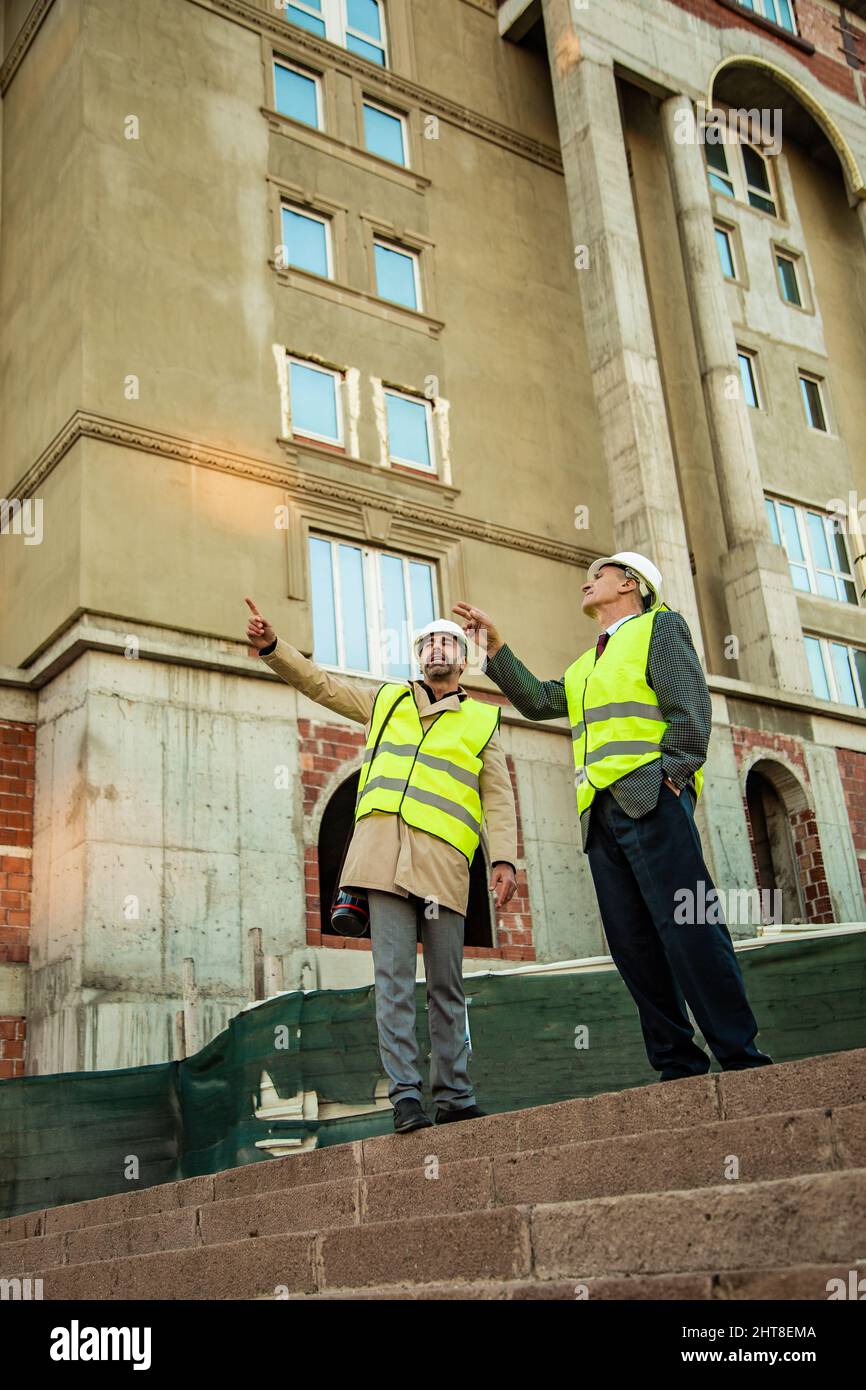 Two senior construction workers are standing and explaining something ...