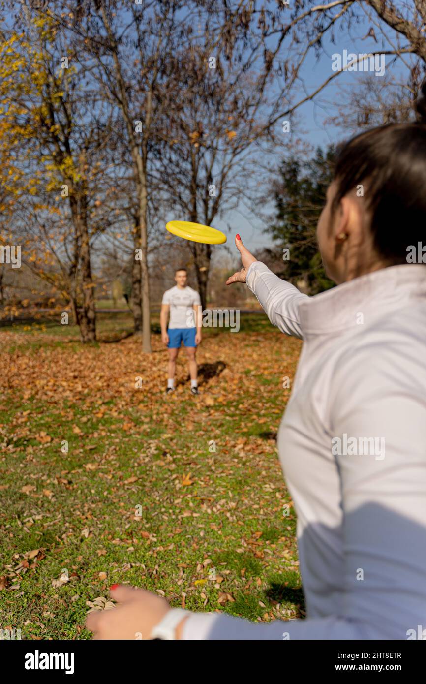 Two attractive and amazing fit friends are playing frisbee outside ...