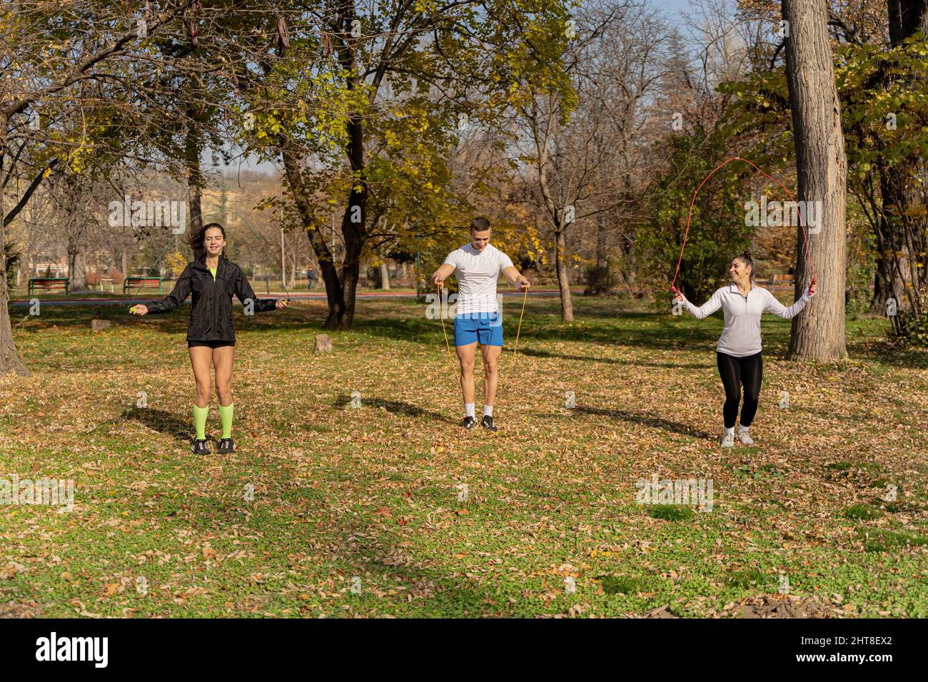 Three attractive and beautiful fit friends are jumping on the rope and ...