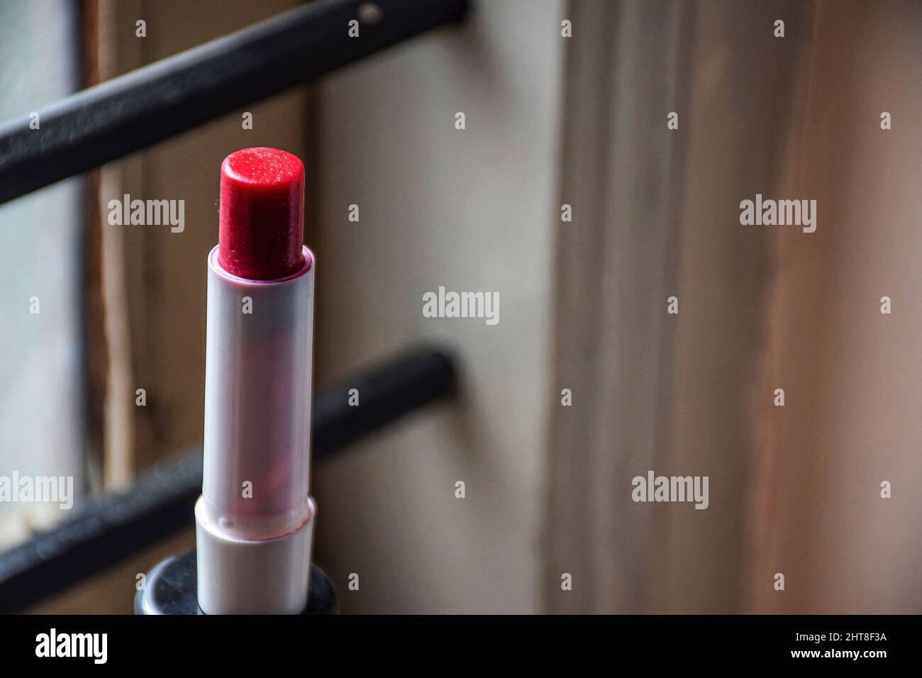 Stock photo of pink color glossy lip balm stick kept near window under ...