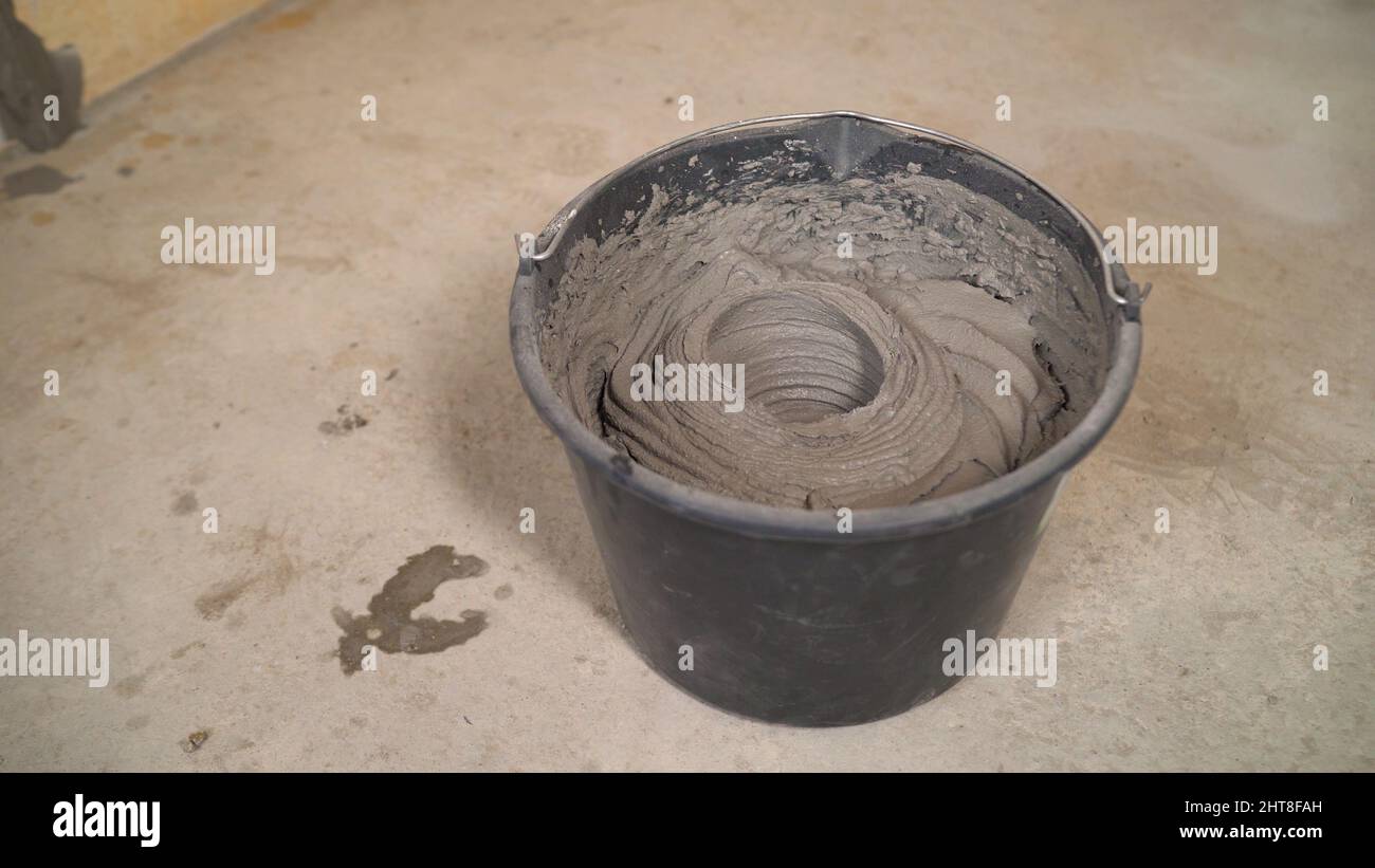 The worker mixes the solution in a bucket. A person mixes cement and ...