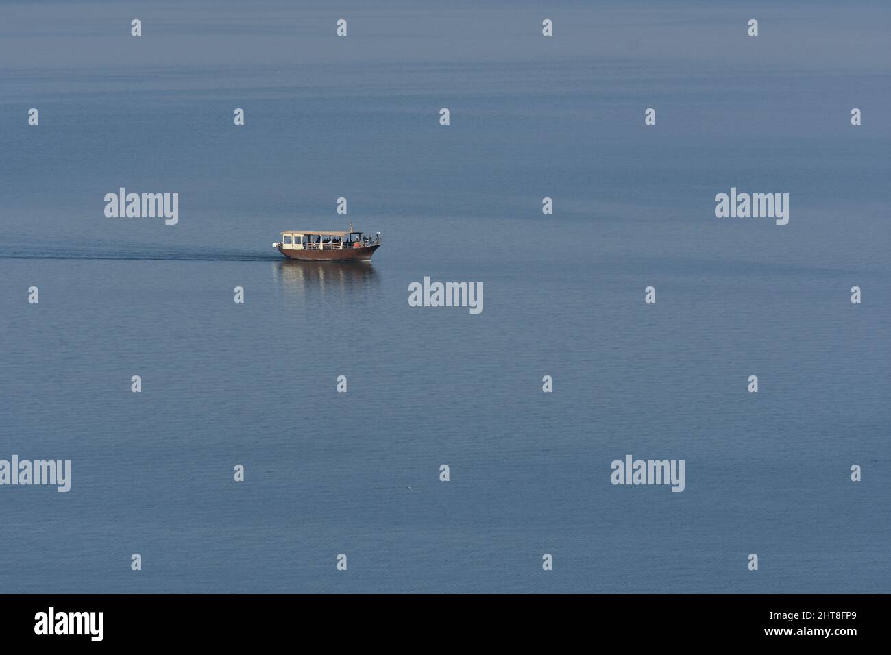 Small tourist boat on the o Galilee sea water under the sunlight in ...