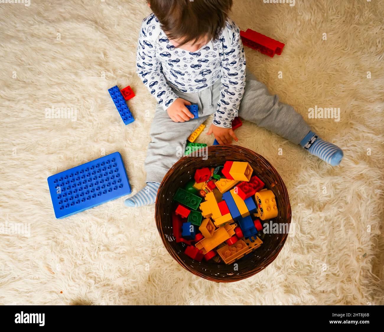 Overhead shot of a young boy playing with Lego Duplo bricks on a carpet ...