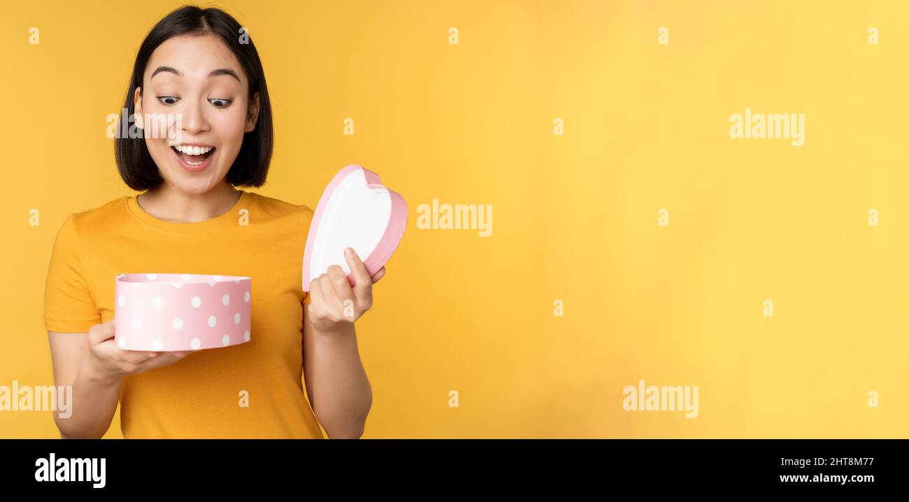 Portrait of excited asian woman, open gift box with surprised happy ...