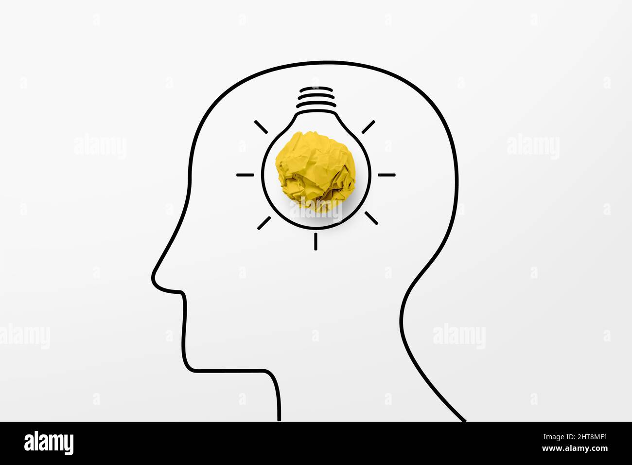 Yellow crumpled paper on the drawn light bulb inside the human head ...