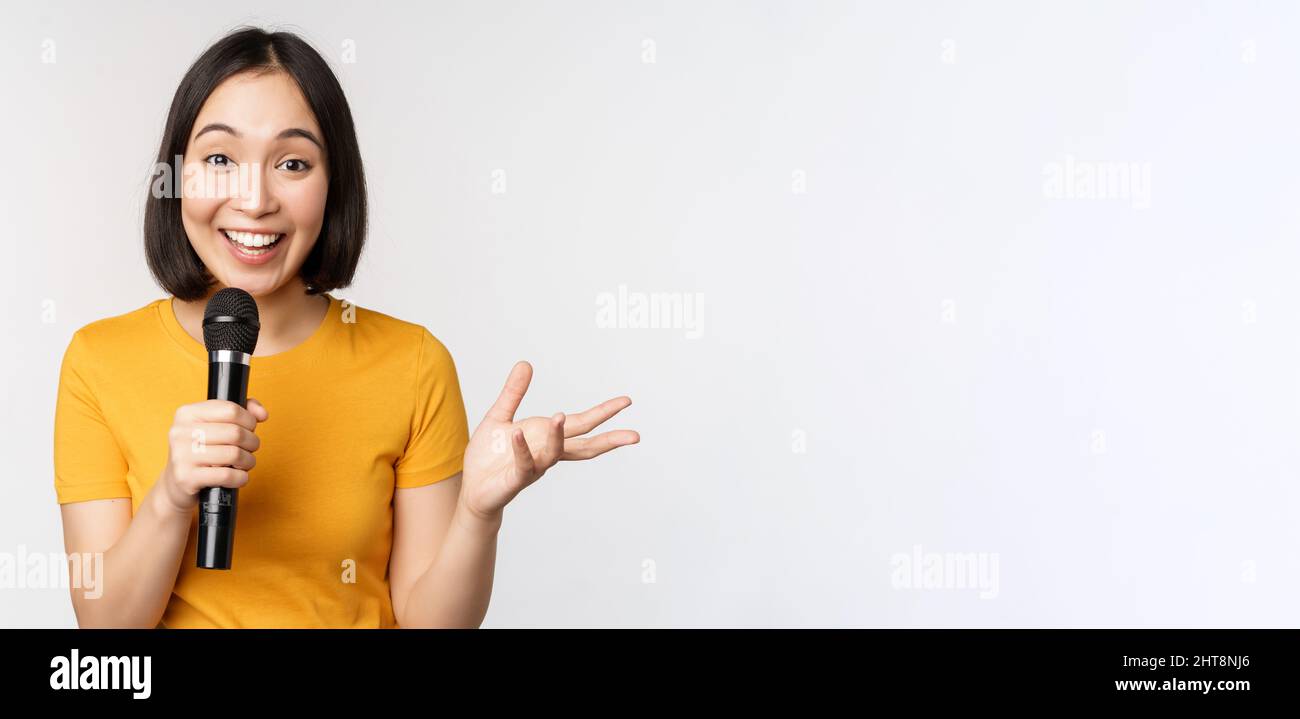 Image of young asian woman talking in microphone, perfom with mic ...