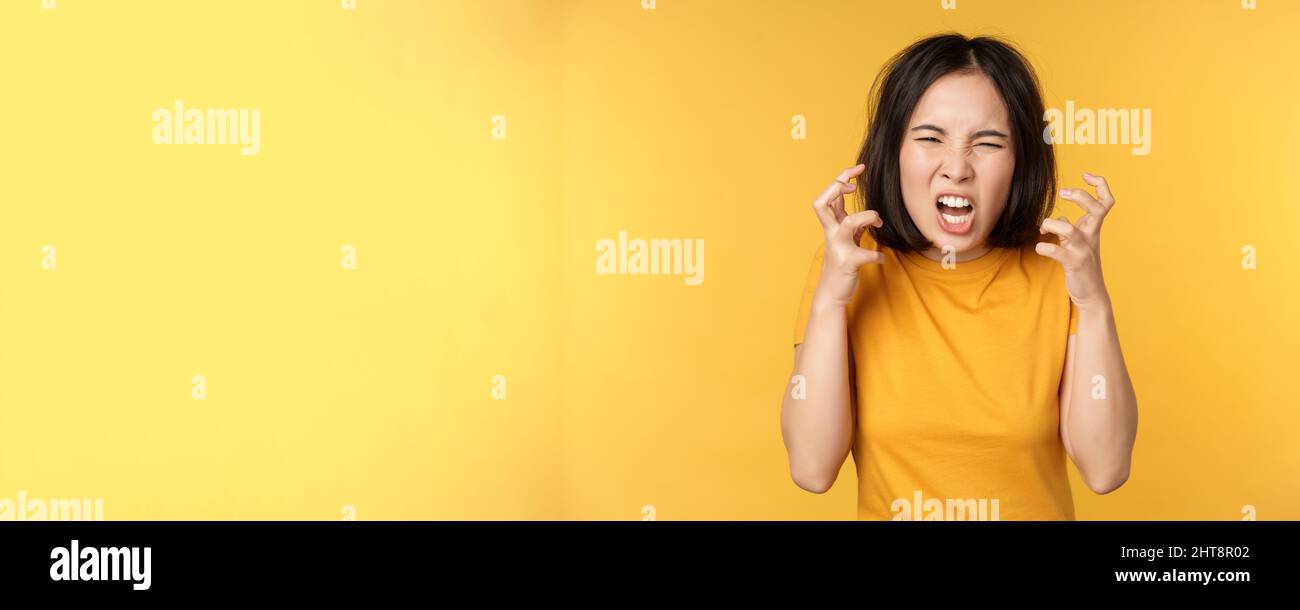 Image of angry asian woman, shouting and cursing, looking outraged ...