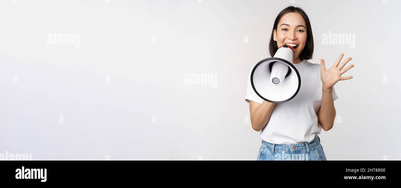 Happy asian woman shouting at megaphone, making announcement ...