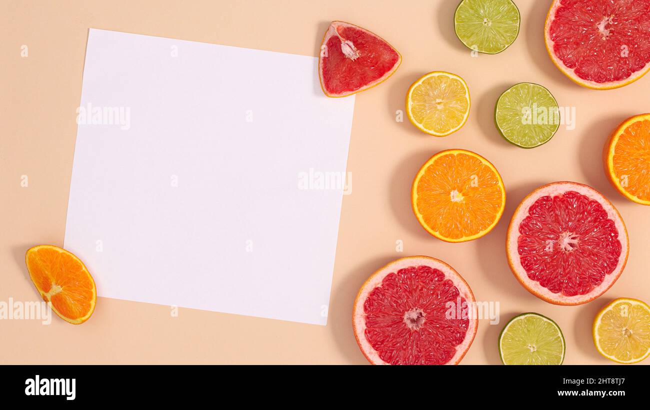 Sliced citrus fruits layout with paper card note on pastel beige ...