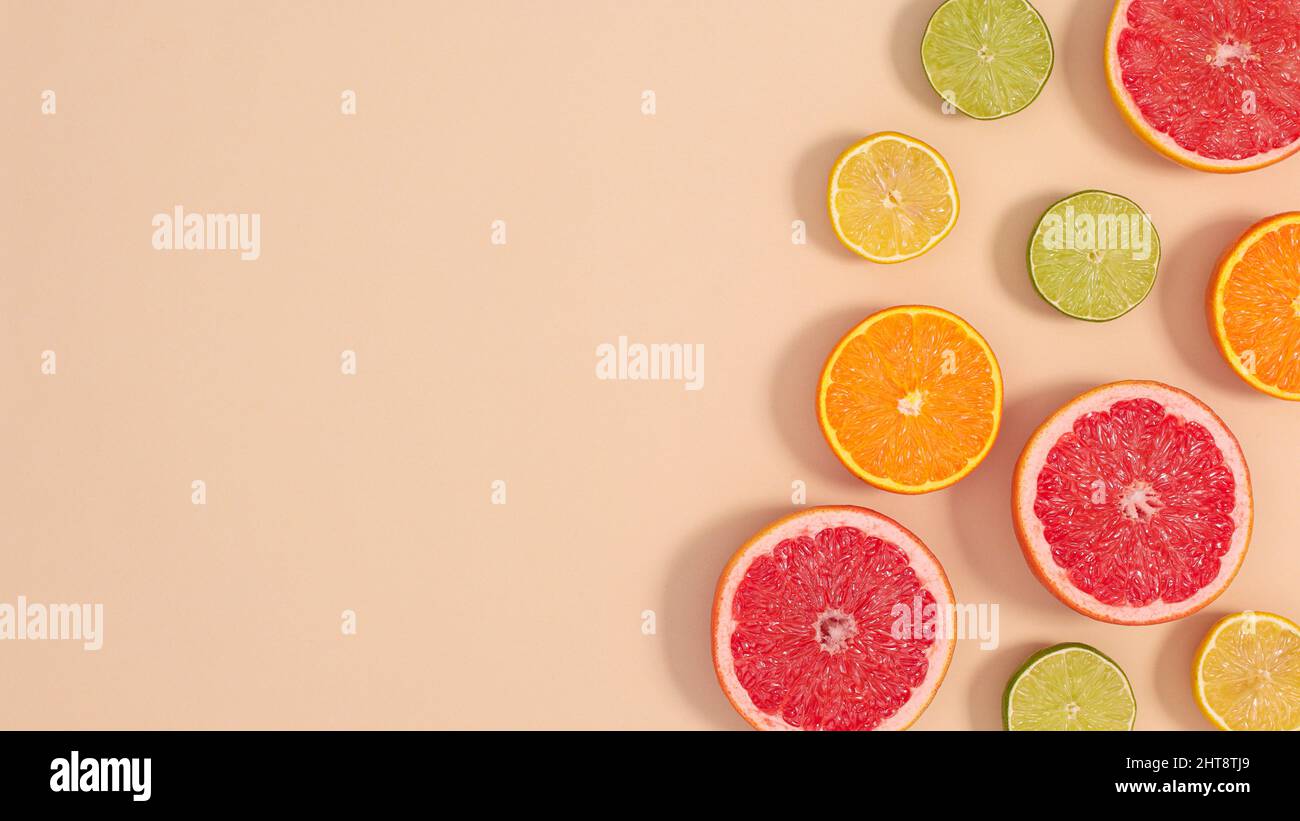 Sliced citrus fruits layout on right side of pastel beige background ...