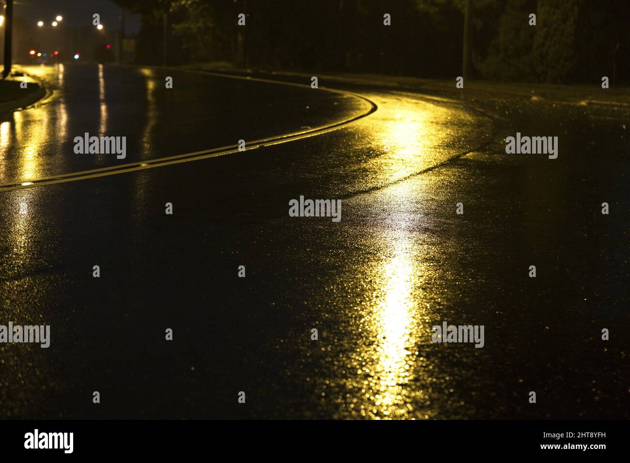 Dark wet road at night illuminated by yellow street lights Stock Photo ...
