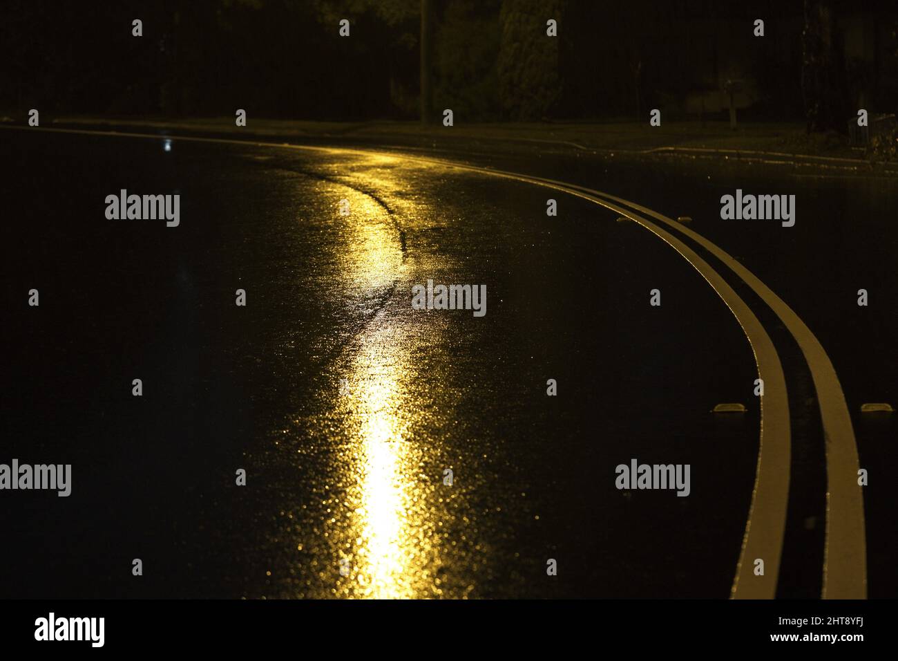 Dark wet road at night illuminated by yellow street lights Stock Photo ...