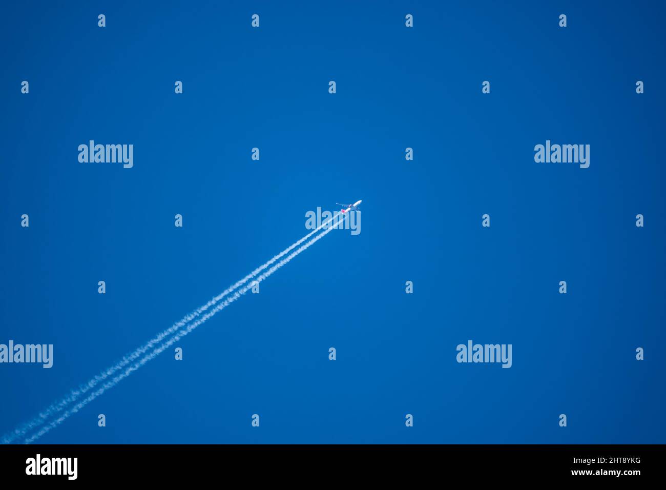 high altitude contrails from a twin engine jet airliner in a deep blue ...