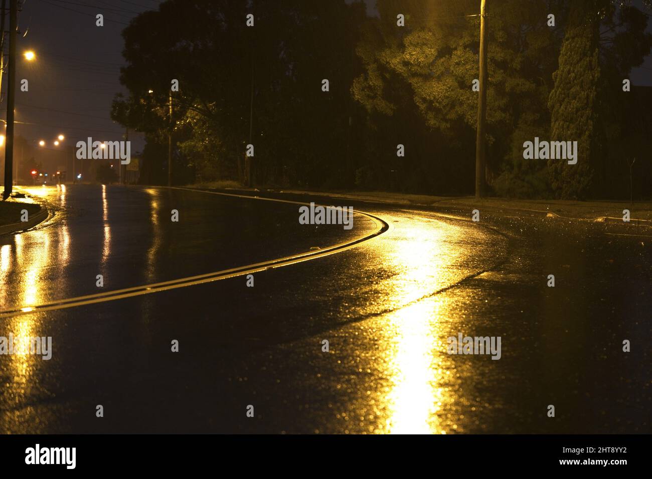 Dark wet road at night illuminated by yellow street lights Stock Photo ...