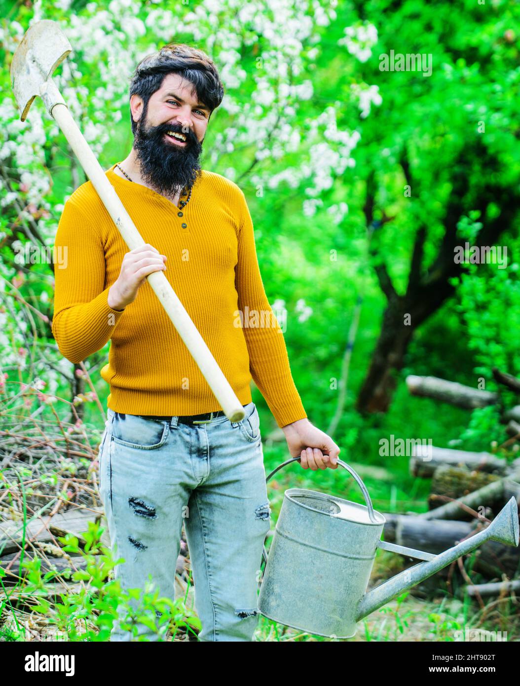 Bearded man with watering can and shovel. Farmer working in garden ...