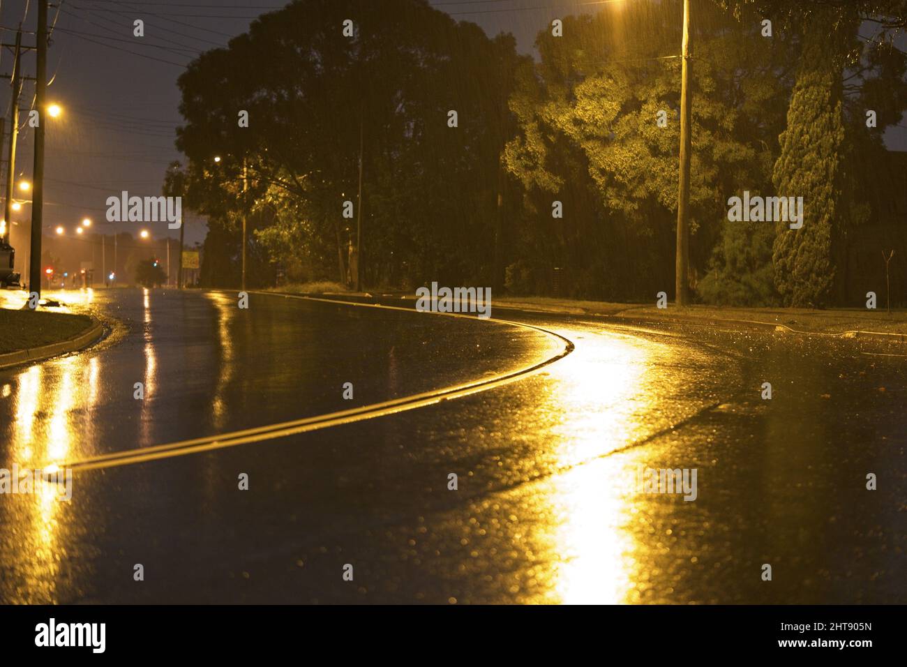 A dark wet road at night illuminated by yellow street lights Stock ...