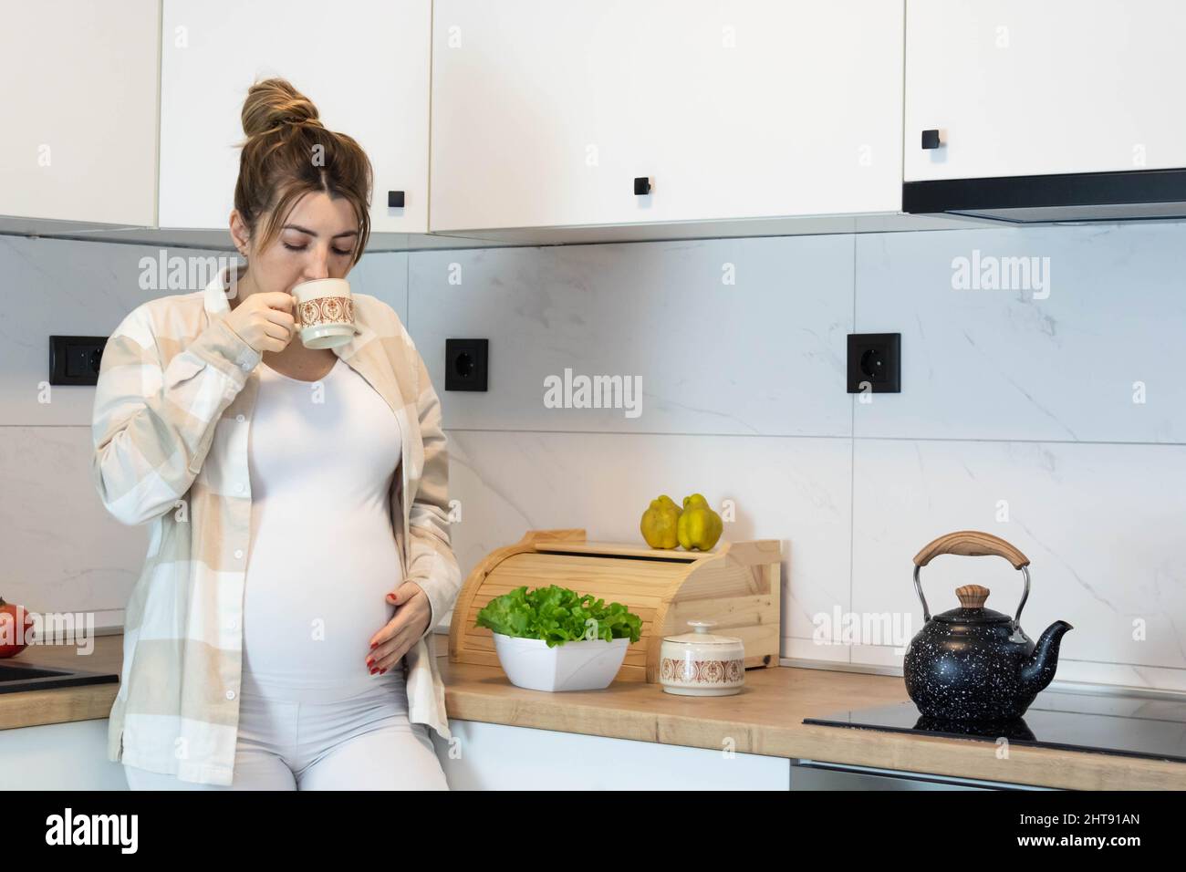 A Caucasian pregnant female drinking tea in the kitchen Stock Photo - Alamy