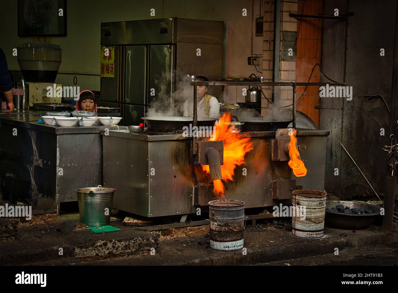 Fire burning at a street food market in Xian, China with people cooking ...
