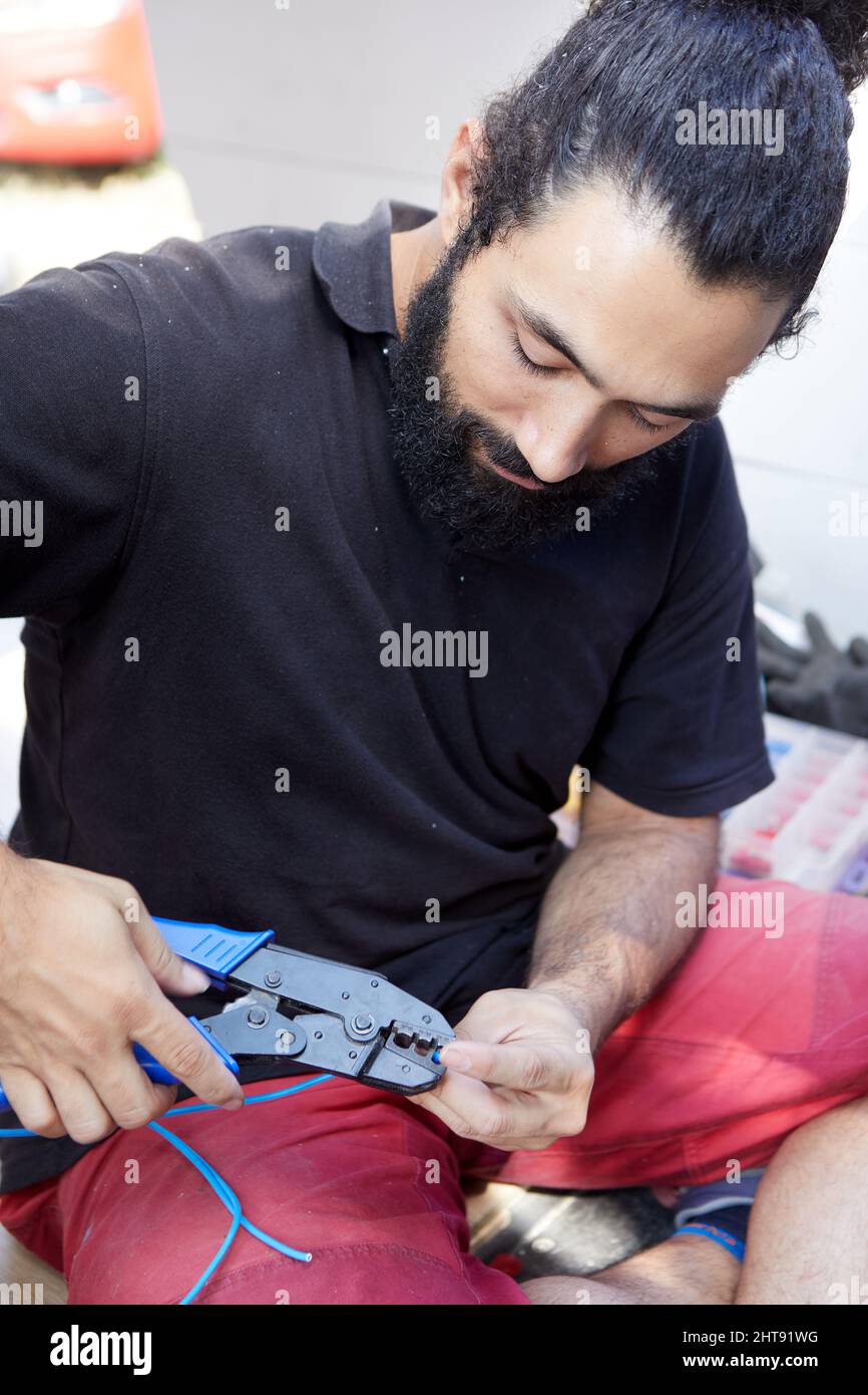 Hispanic male preparing cable with crimping tool Stock Photo - Alamy