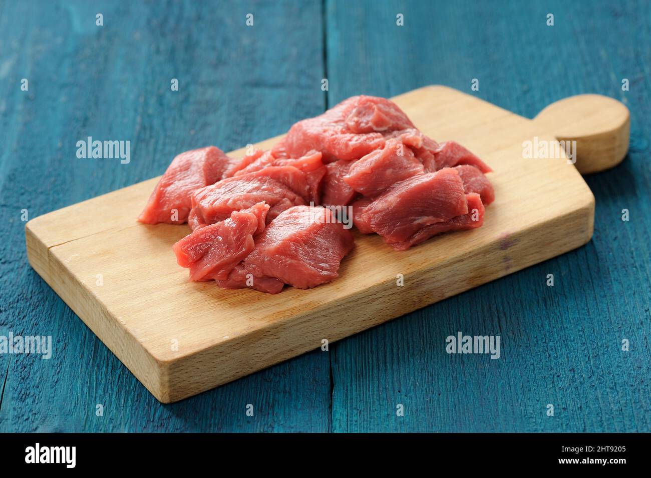 Raw lean meat cuts on wooden board on deep blue background horizontal ...