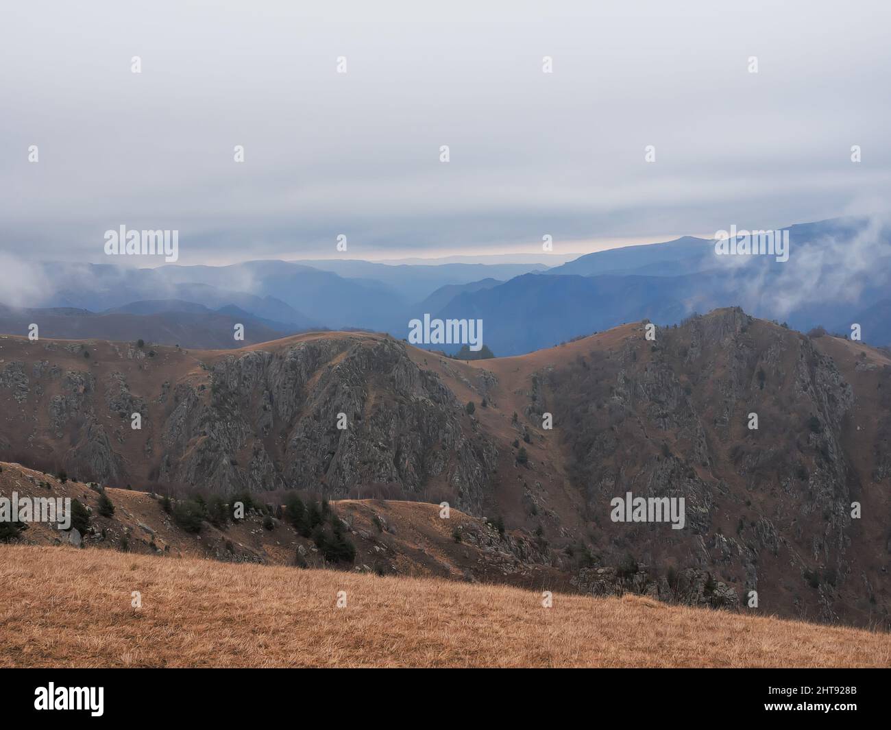 High and steep Caucasian mountains with low-dropping clouds above them ...