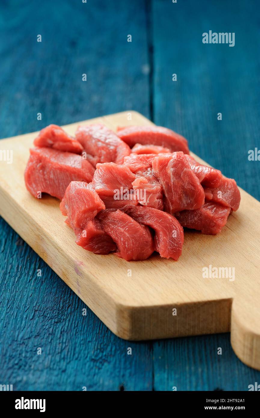Raw lean meat cuts on wooden board on deep blue background vertical ...
