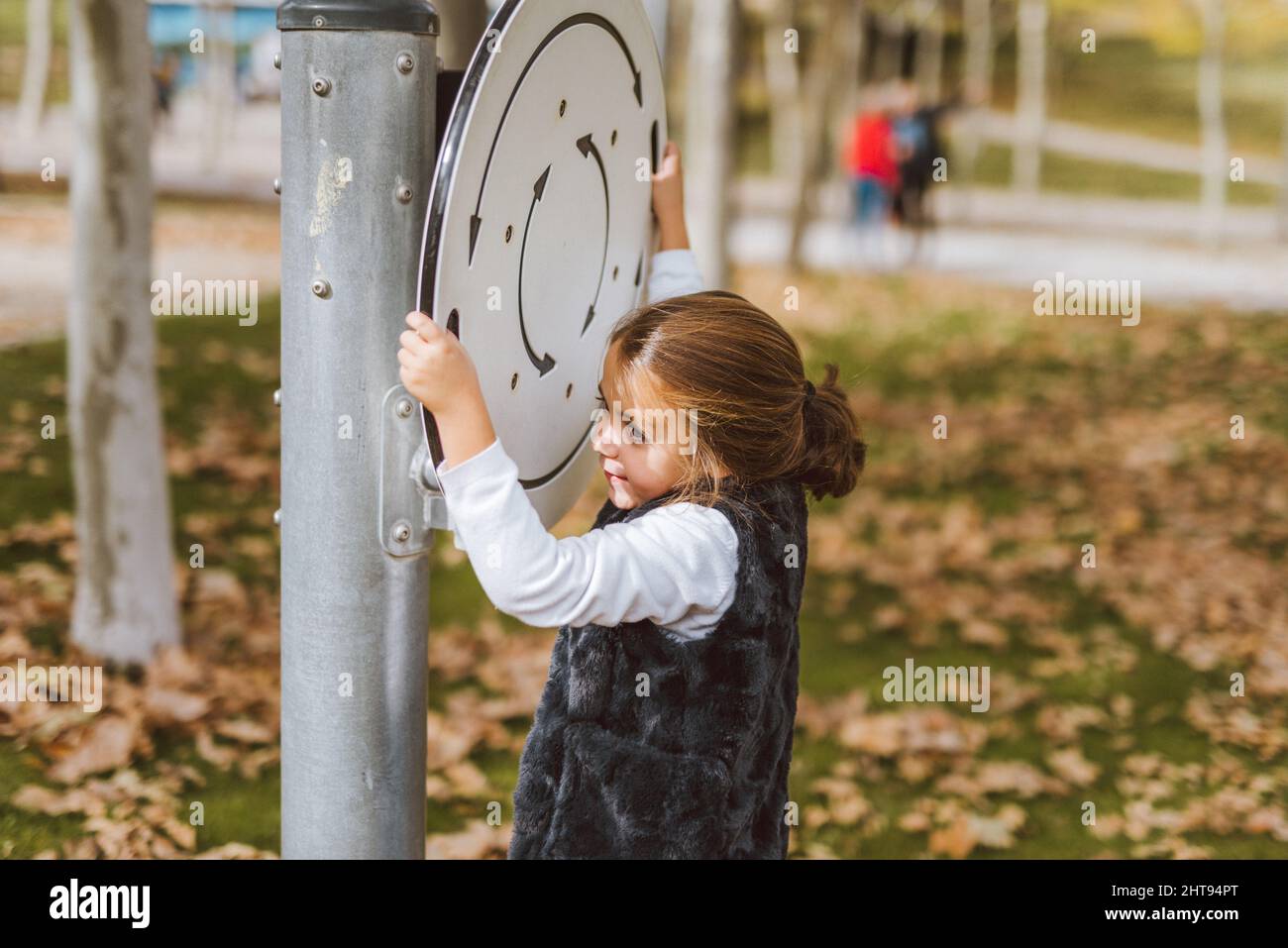 Cute, little girl smiling while spinning a wheel in the exercise park ...