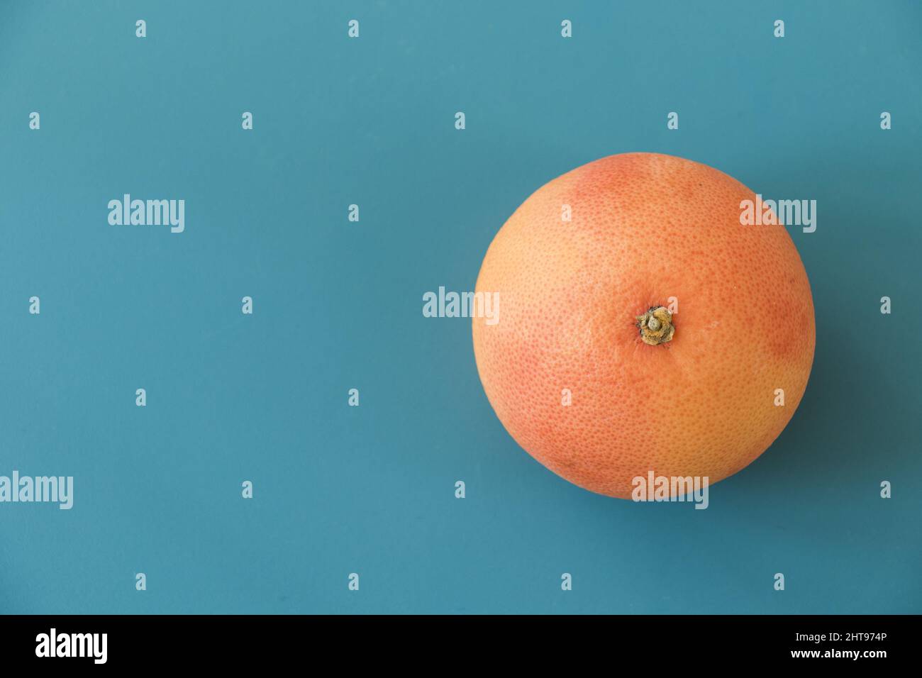 Closeup of a grapefruit on the blue background, orange and blue colors ...