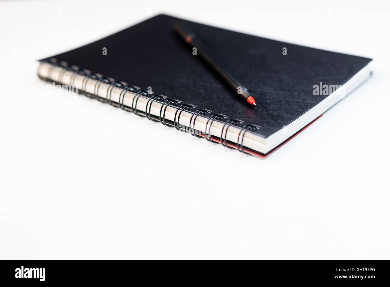 Closed black spiral binding notebook with pen isolated on white ...