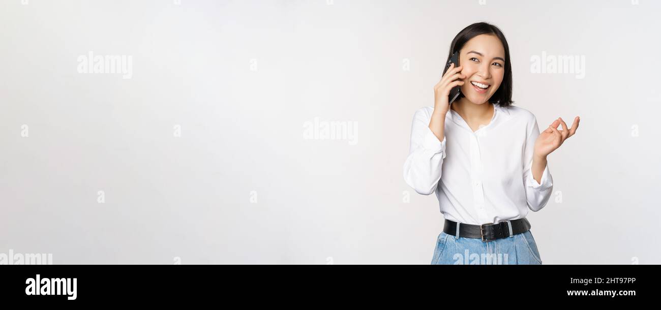 Friendly smiling asian woman talking on phone, girl on call, holding ...