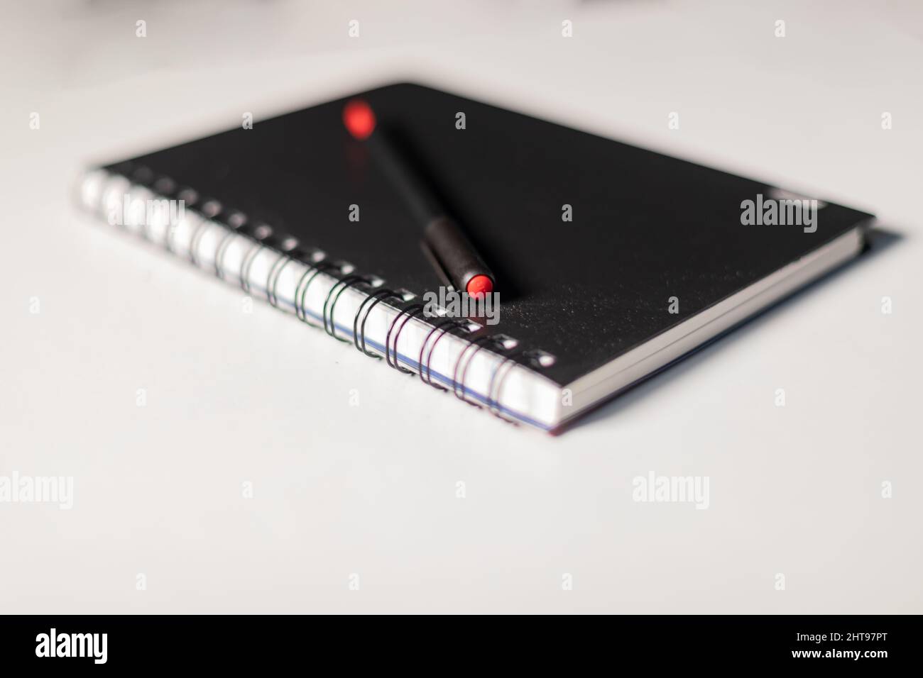 Closed black spiral binding notebook with pen isolated on white ...