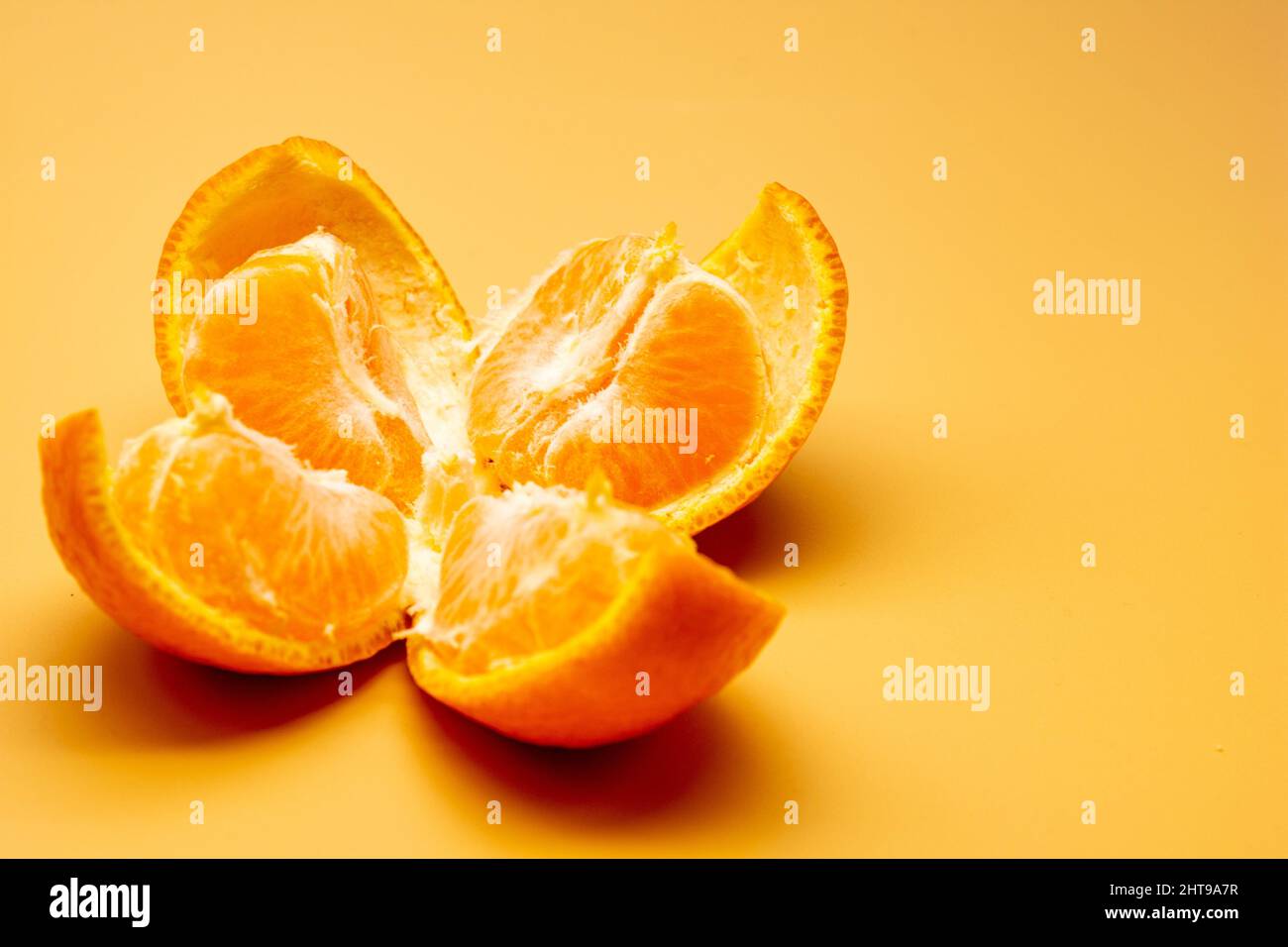 Closeup of a peeled juicy, sweet mandarin on the orange surface Stock ...