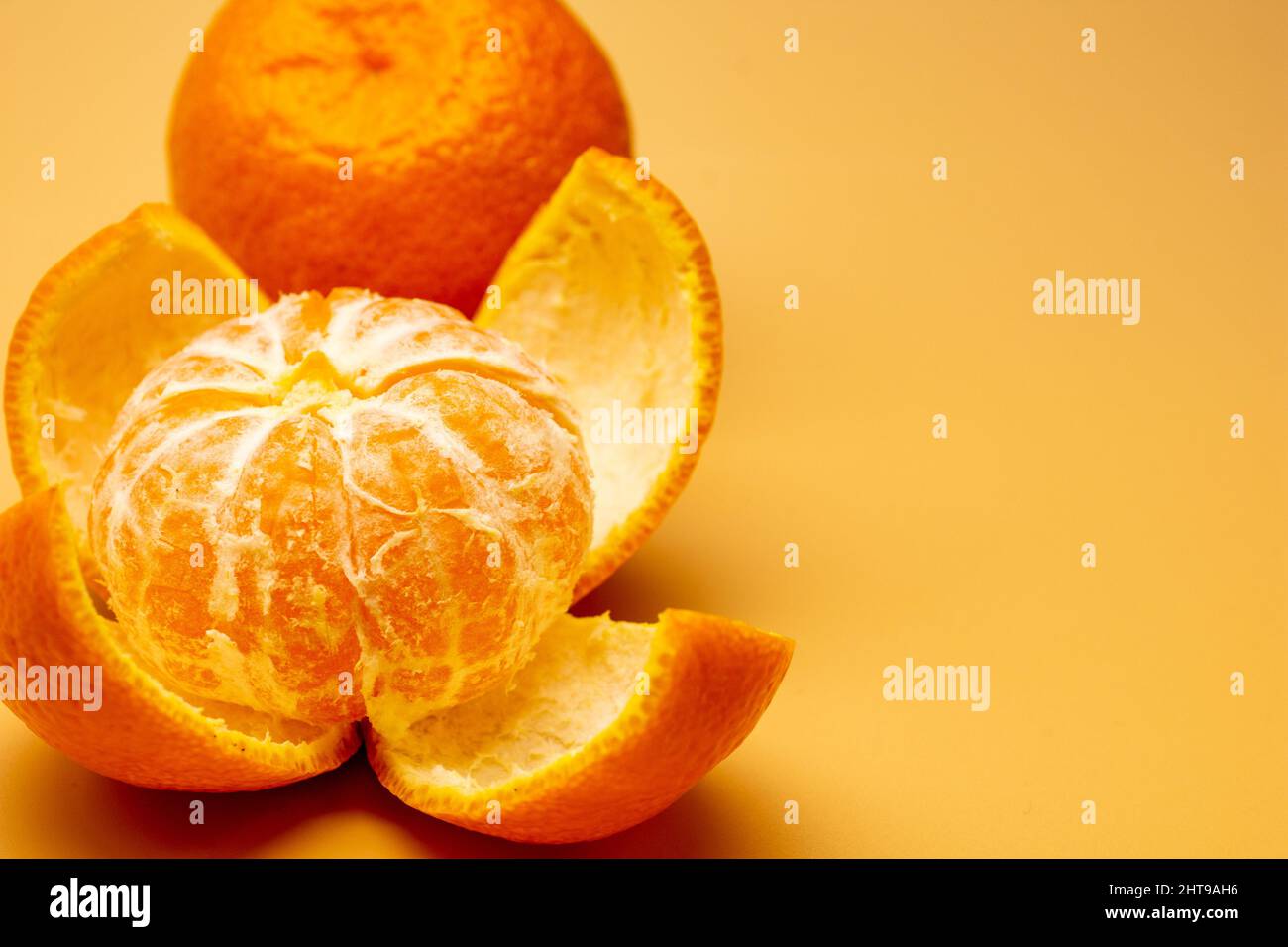 Closeup of a peeled juicy, sweet mandarin on the orange surface Stock ...