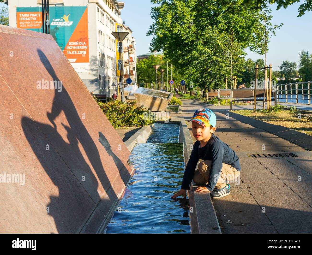 Young boy touching water by a sidewalk of a park Stock Photo - Alamy