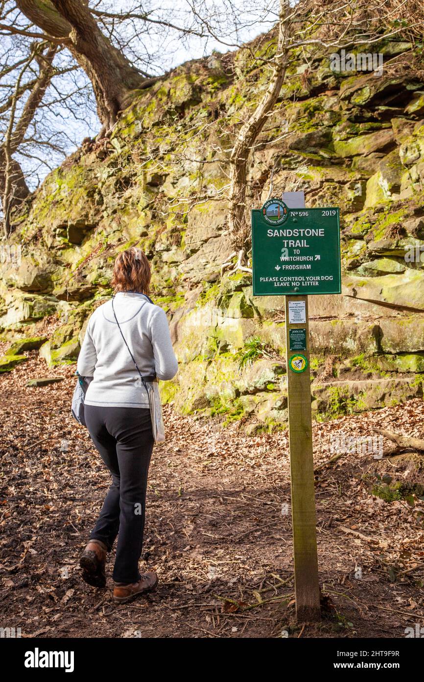 Woman walking past a waymarker sign post on the Sandstone trail long ...
