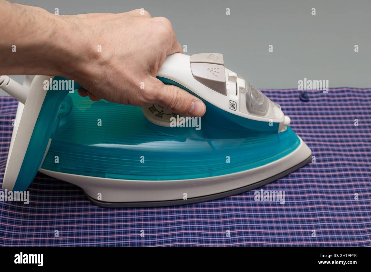 a hand holds an iron with which it irons a shirt in a cage. High ...