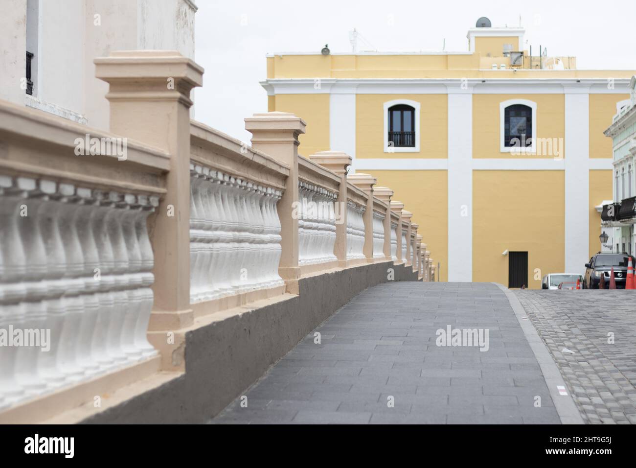 view of a walkway street with marble railing and a yellow building in ...