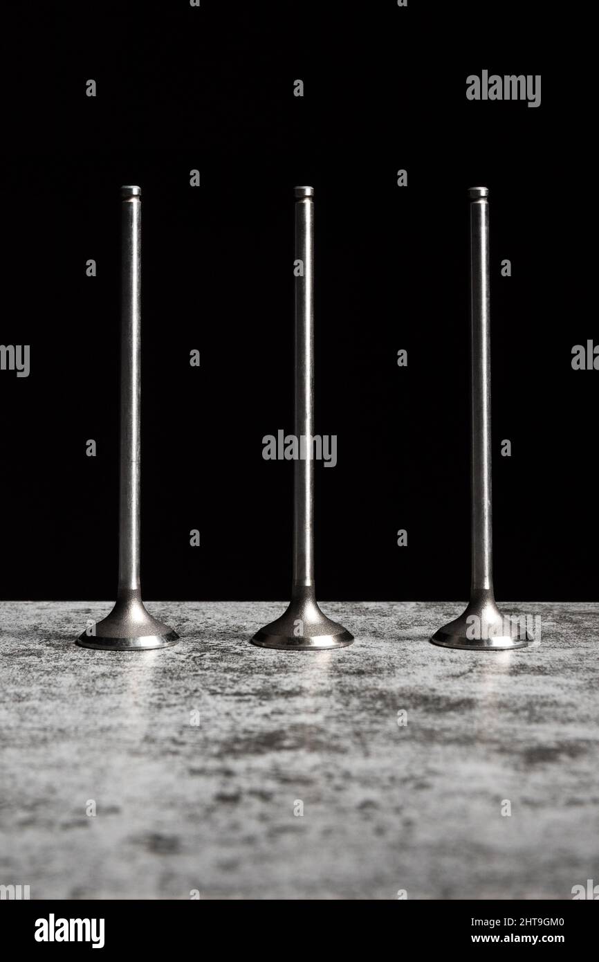 Three car engine valves on black background. Part of an internal ...
