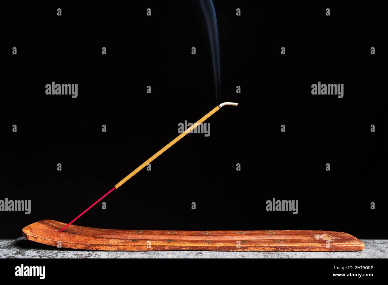 Side view of incense stick stands on a wooden stand isolated on a black ...