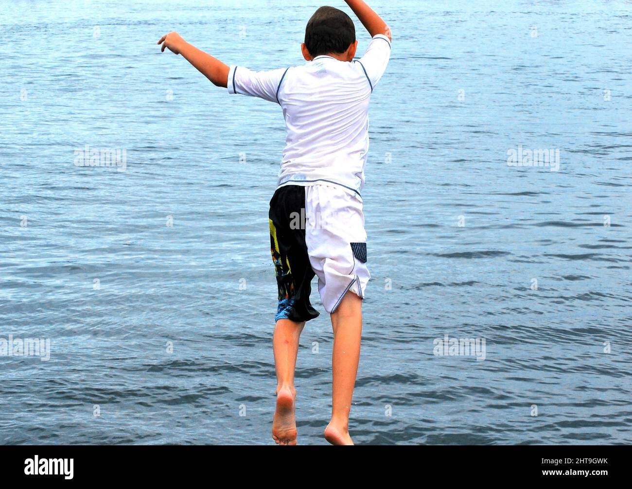 View of a young boy jumping into the water Stock Photo - Alamy