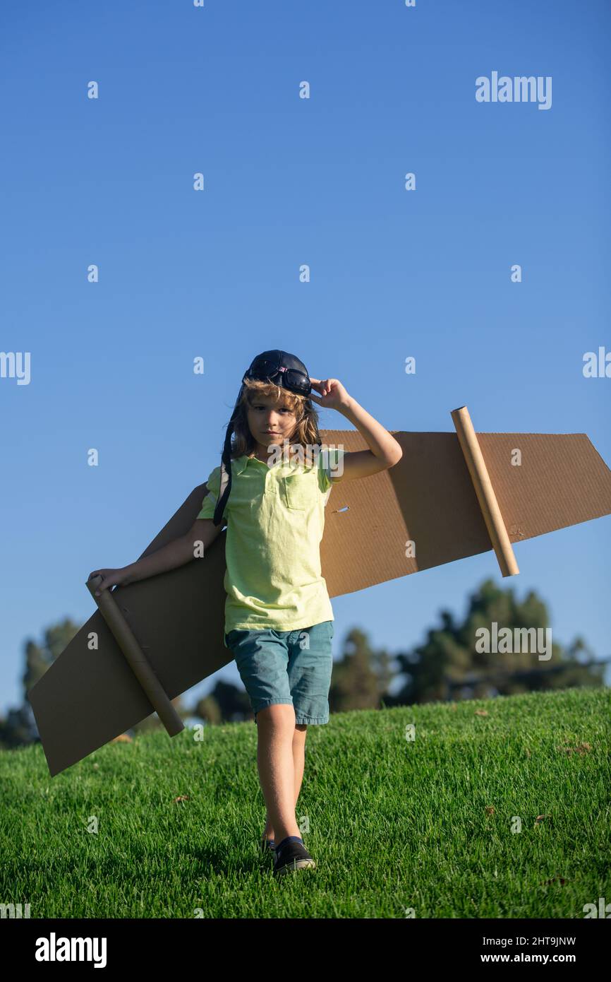 Kid boy playing with cardboard wings. Child in summer field. Kids ...