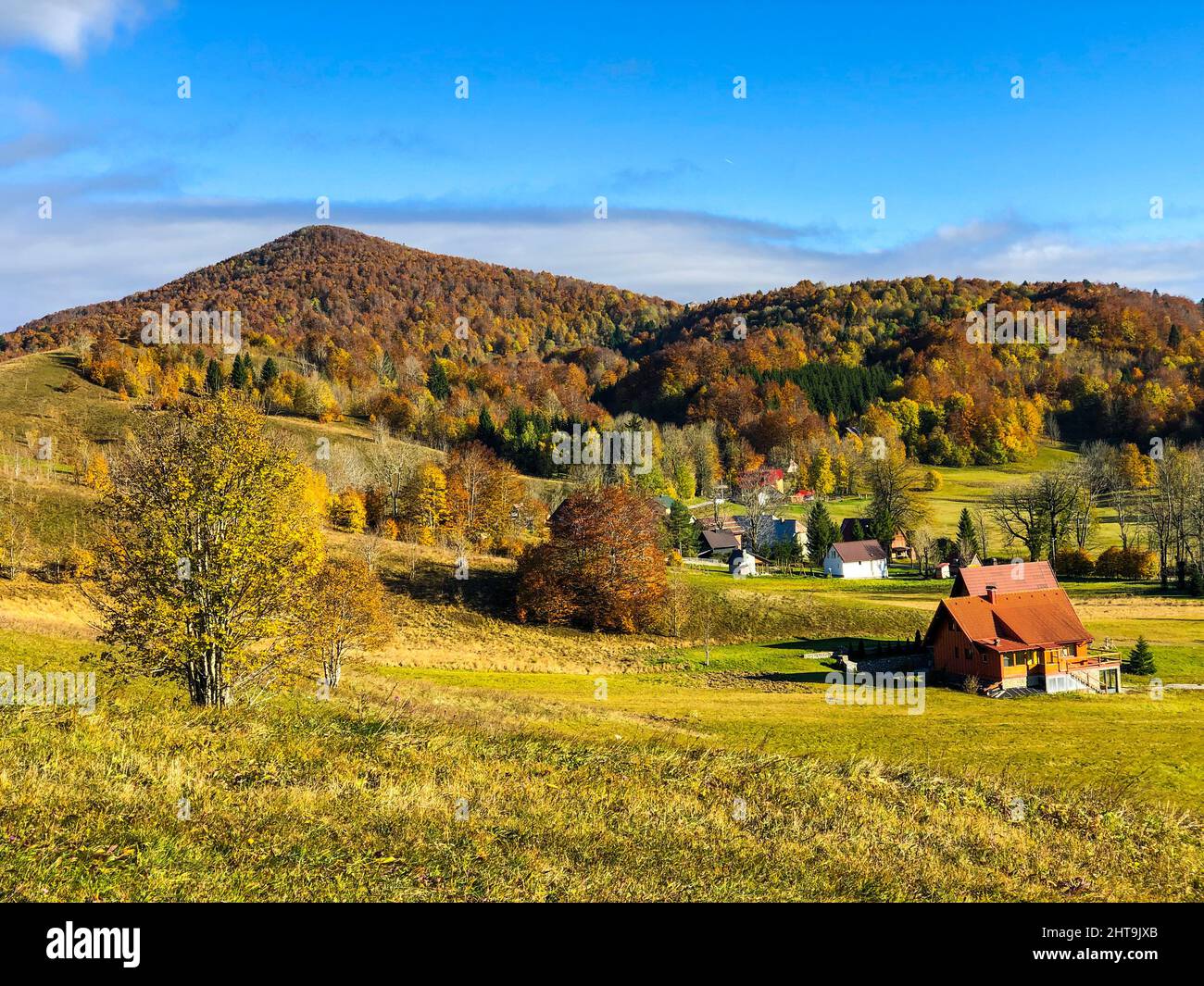 Photo of a rural landscape with forest hills, grasslands and houses ...