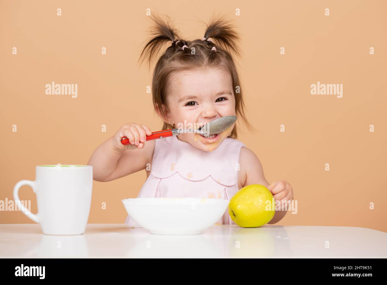 Baby eating kids food. Babys first meal. The child eats on his own with ...