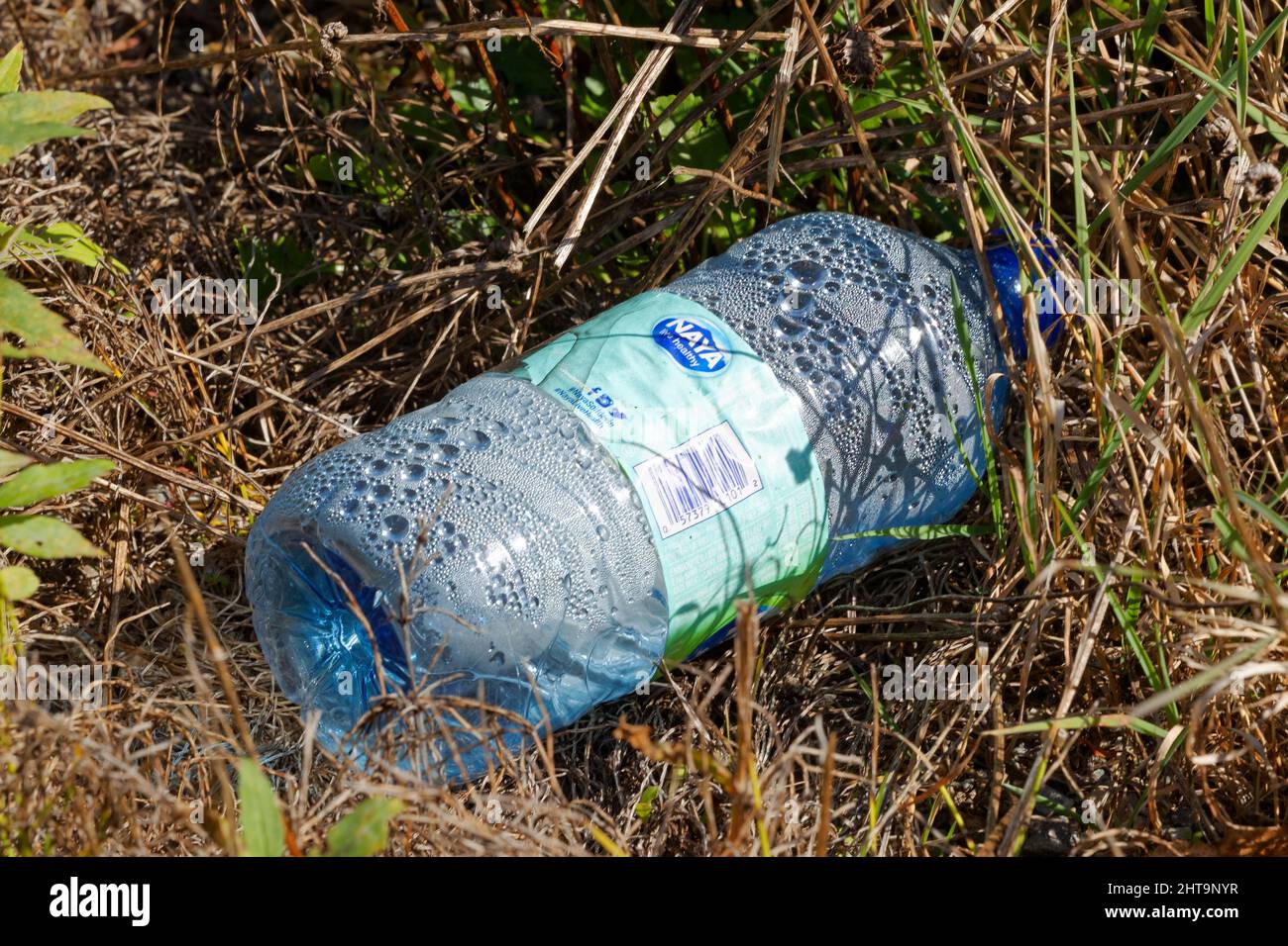 A partially empty plastic water bottle laying on the ground. Quebec ...