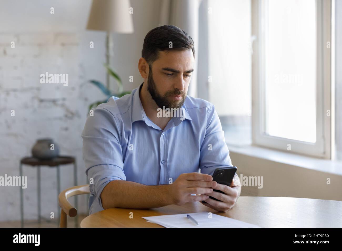 Young serious man sit at table with modern cellphone Stock Photo - Alamy