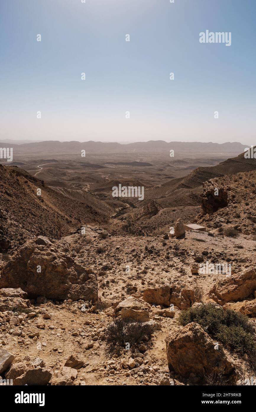 Vertical shot of dry desert with rough rocky cliffs on the background ...