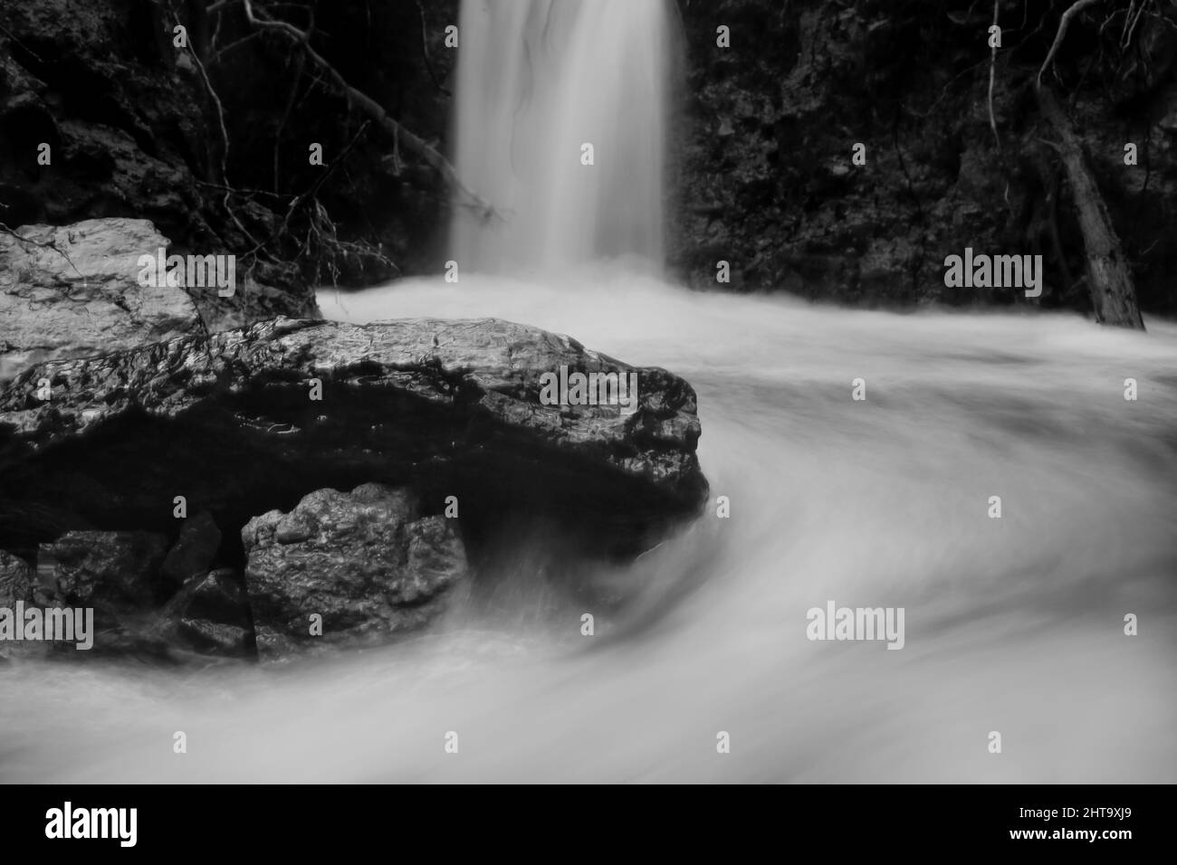 Grayscale shot of water flowing downstream on a rocky waterfall with ...