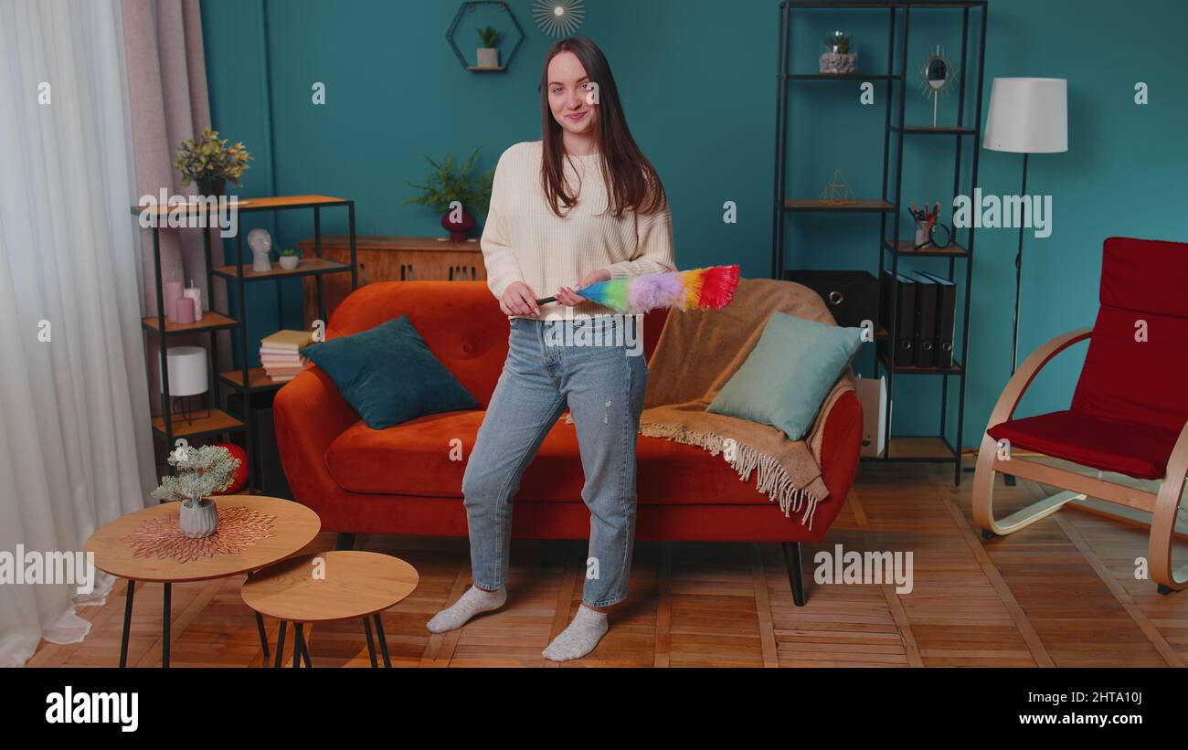Happy young woman dusting furniture caring for hygiene using colorful ...
