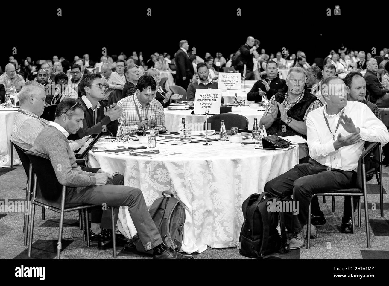 Grayscale of delegates at a round table attending sales convention at ...