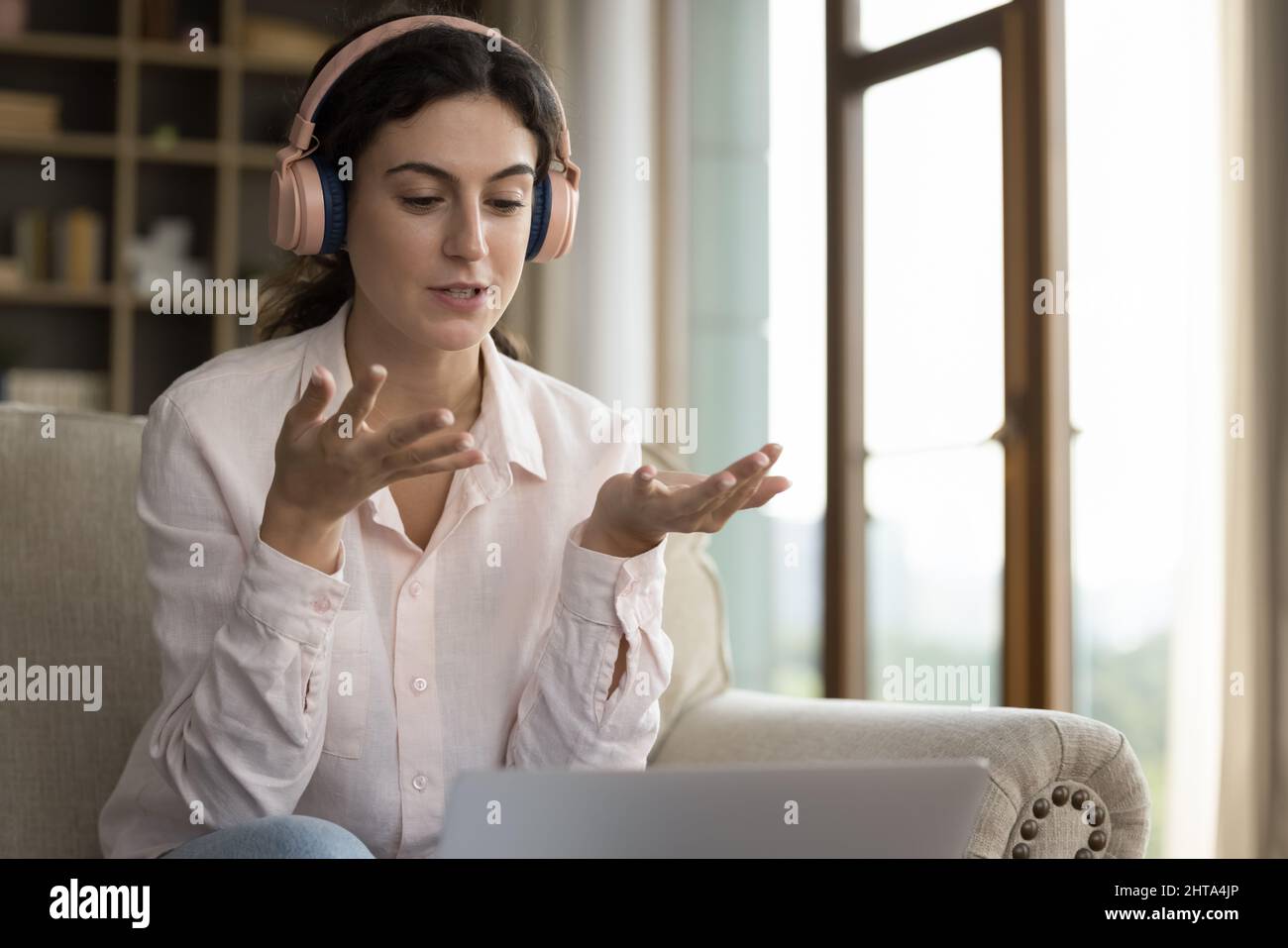 Concentrated beautiful young Hispanic woman holding video call ...